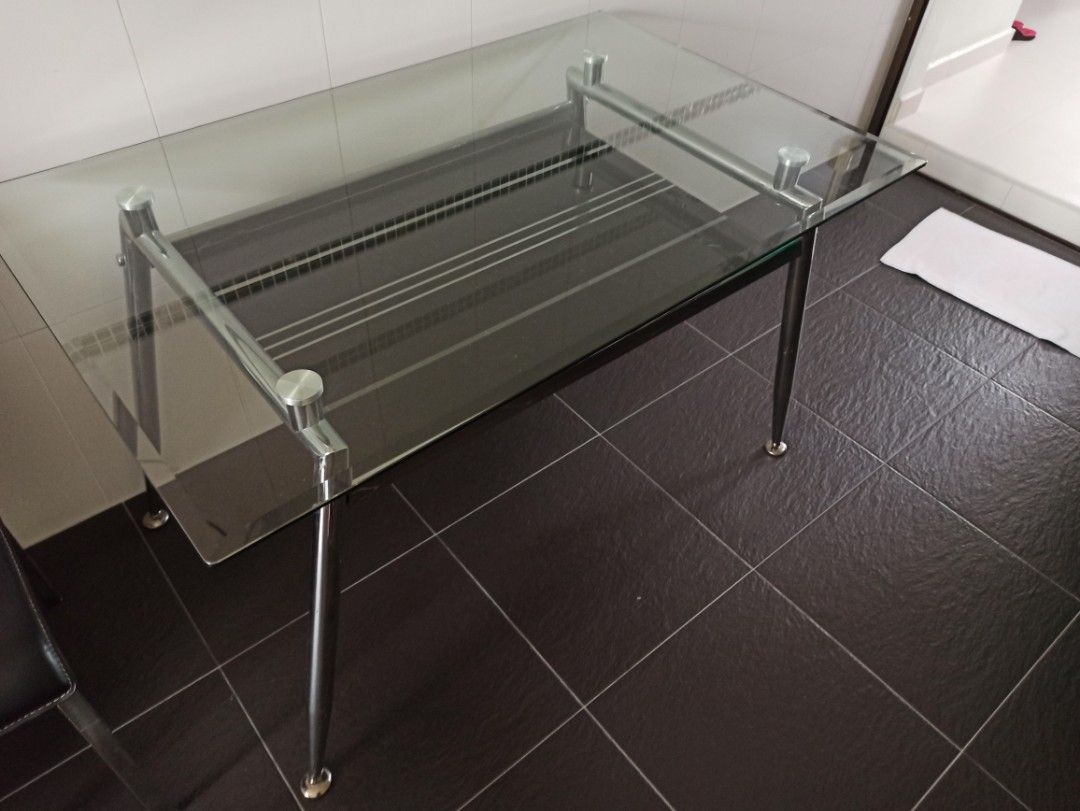 Shiny glass table with metallic stand and extra space beneath ...