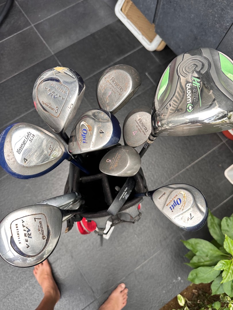 Assorted golf clubs, from driver to woods, to loose pieces irons and a ...